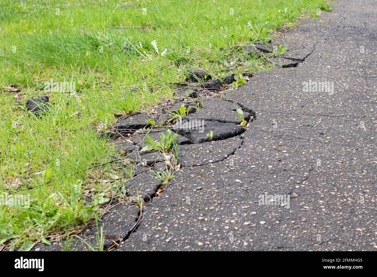Broken asphalt pavement and green grass close up Stock Photo - Alamy