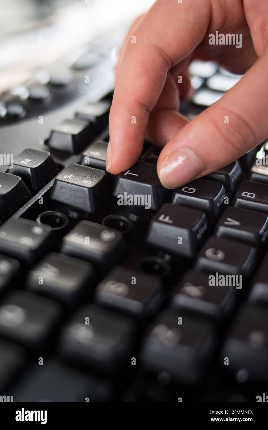 Hand placing a black key in a black keyboard that doesnt have some keys ...