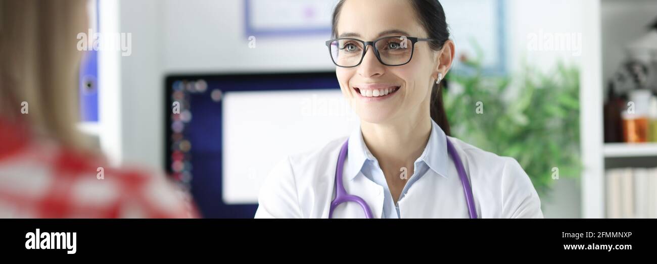 Smiling portrait of doctor in glasses conducts an appointment with ...