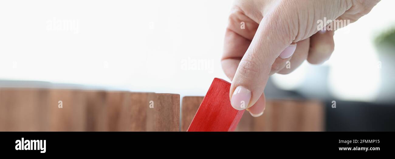 Woman's hand takes out red wooden rectangle Stock Photo - Alamy