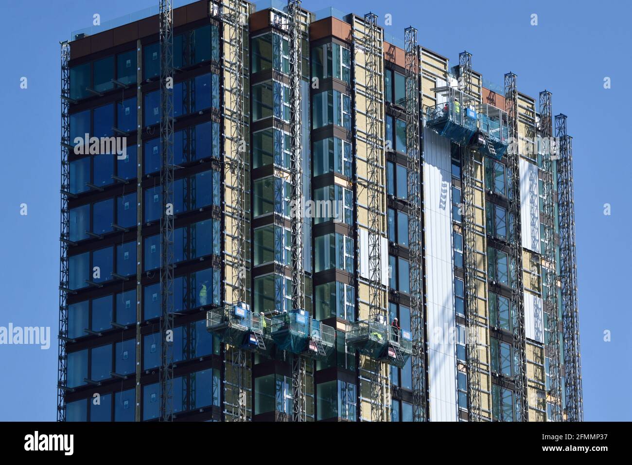 Construction workers in cradles building a high-rise apartment block in ...