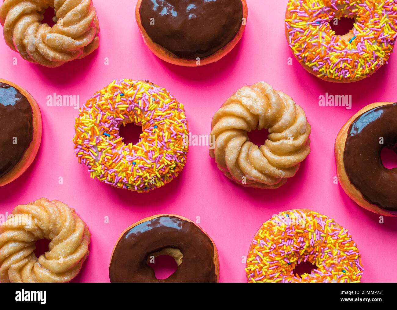 Overhead of assorted donuts against a bright pink background Stock ...