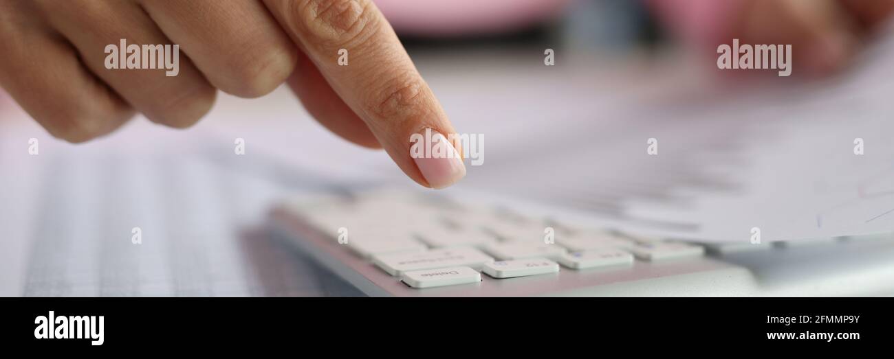 Woman's finger above computer keyboard contains documents with ...