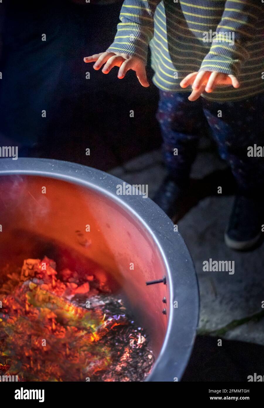 Child warming hands in front of a fire pit Stock Photo - Alamy