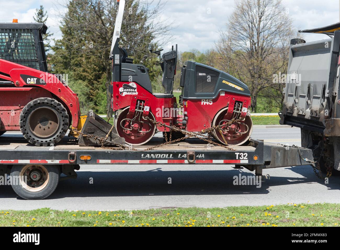 N. American paving vehicles on a flatbed truck being pulled by a heavy ...