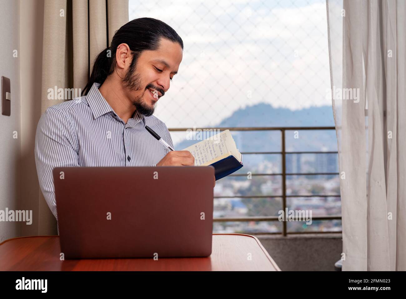 Young latin man working at home in the living room Stock Photo - Alamy