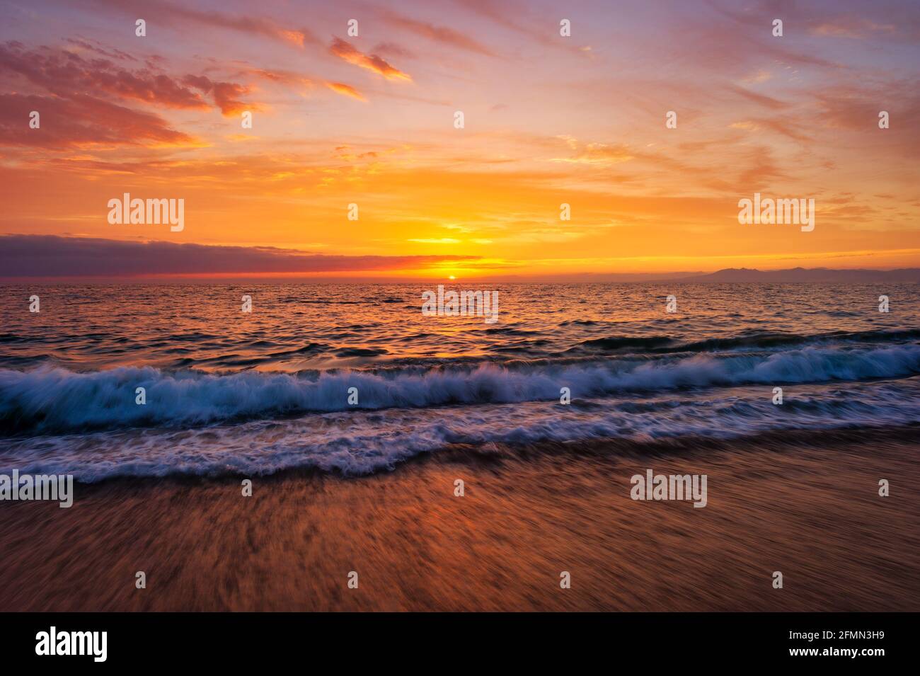 A Colorful Ocean Sunset Sky as a Gentle Wave Rolls to Shore Stock Photo ...