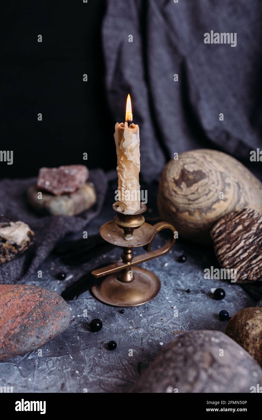 Burning candle and stones on the witch table. Occult, esoteric concept ...