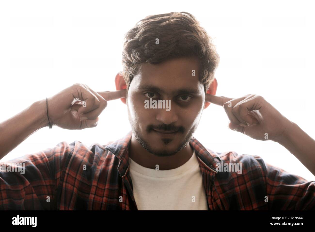 Young indian man putting fingers in ears and don’t want to listen ...