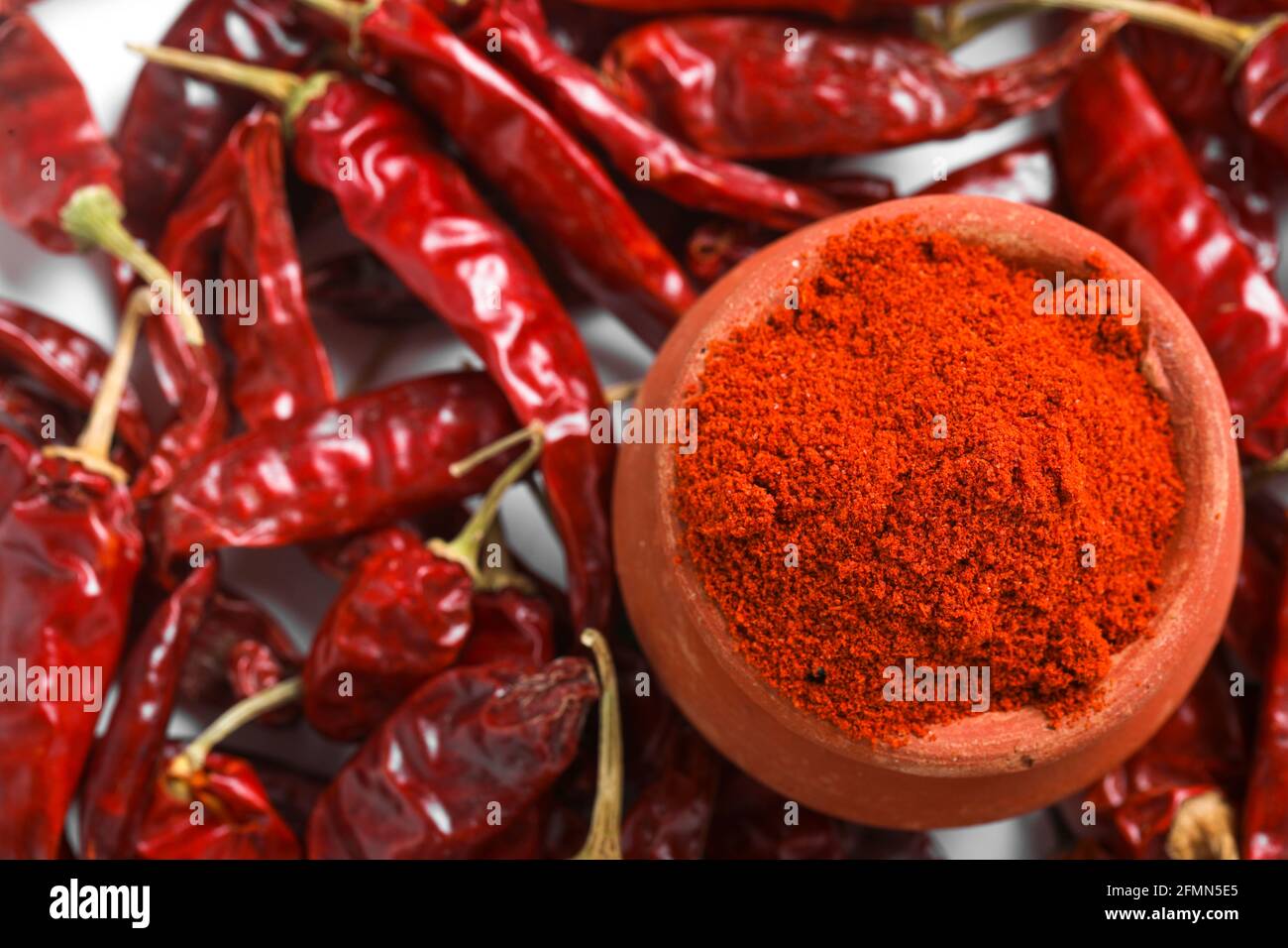 Red Chilli Powder With Dried Red Chillies In Earthen Bowl Stock Photo red-chilli-powder-with-dried-red-chillies-in-earthen-bowl-stock-photo