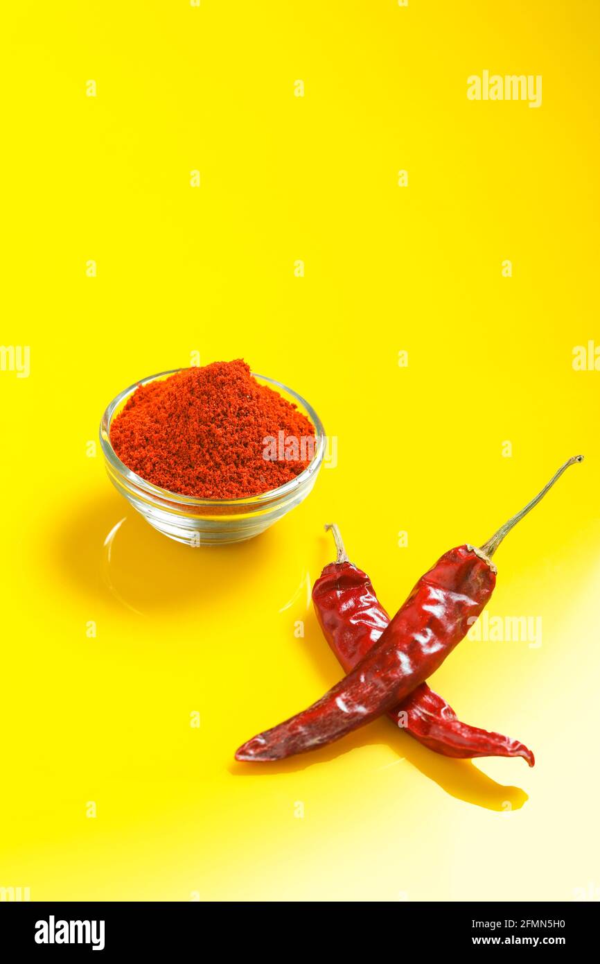 Dry Red chilli with chilli powder in glass bowl on yellow background ...