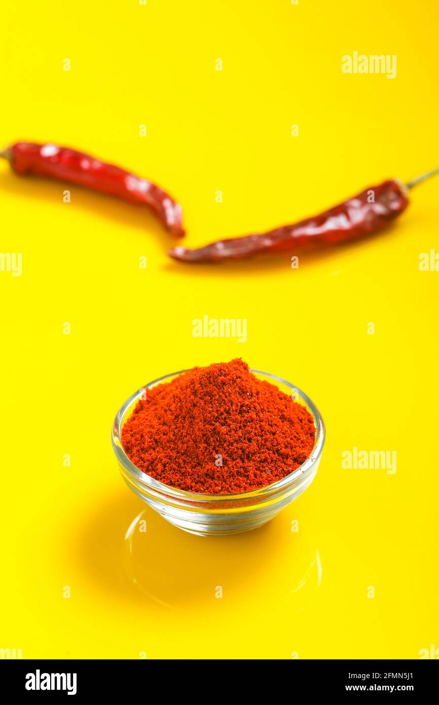 Dry Red chilli with chilli powder in glass bowl on yellow background ...