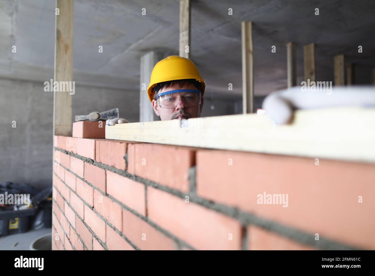 Portrait of builder laying bricks using special tools. Worker building ...