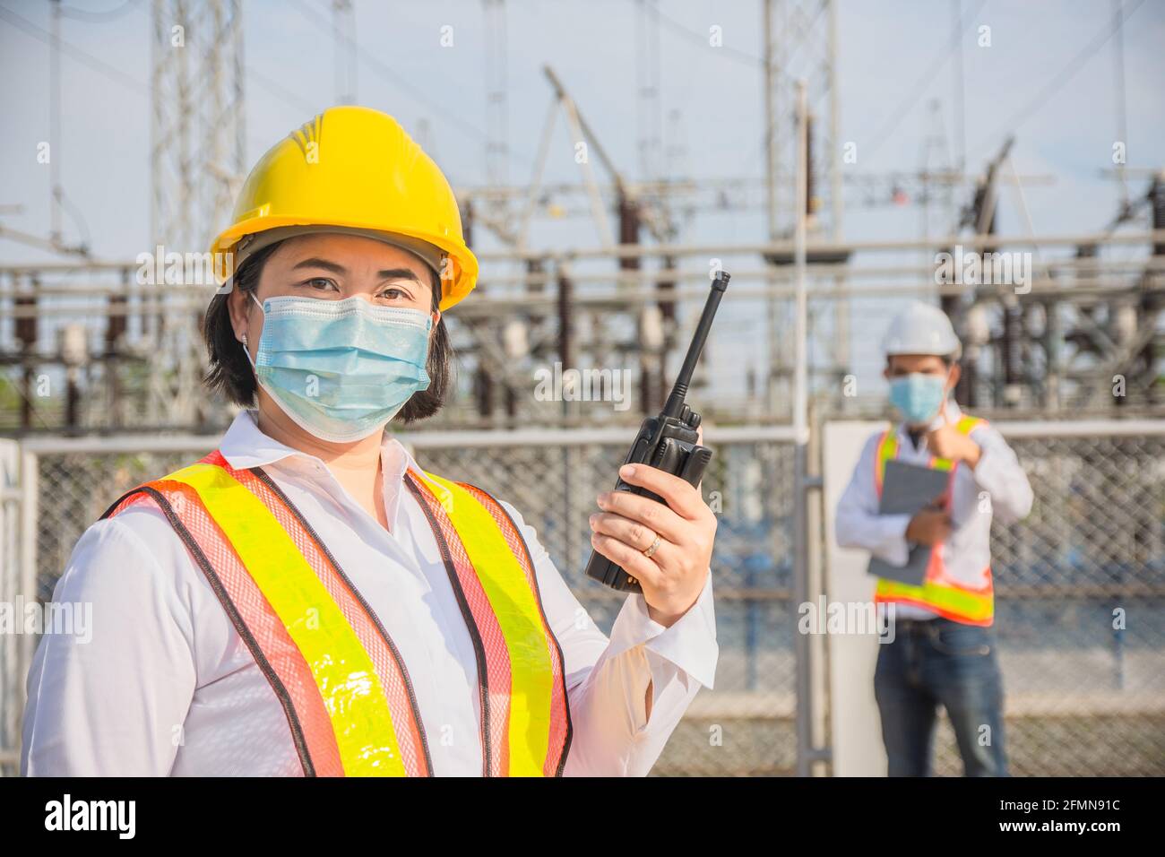 Two Engineer wear facemask teamwork are working industrial electricity ...
