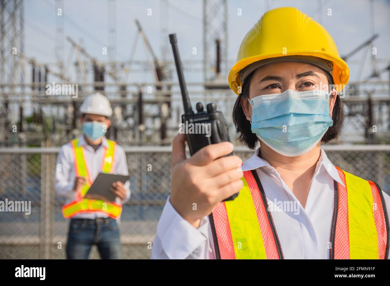 Two Engineer wear facemask teamwork are working industrial electricity ...