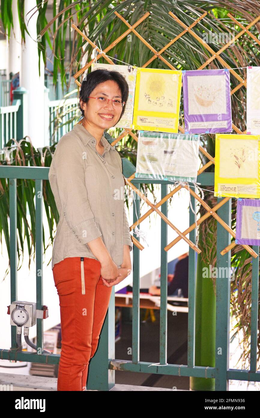 A cute Chinese painter with a big smile standing near her artwork in a ...