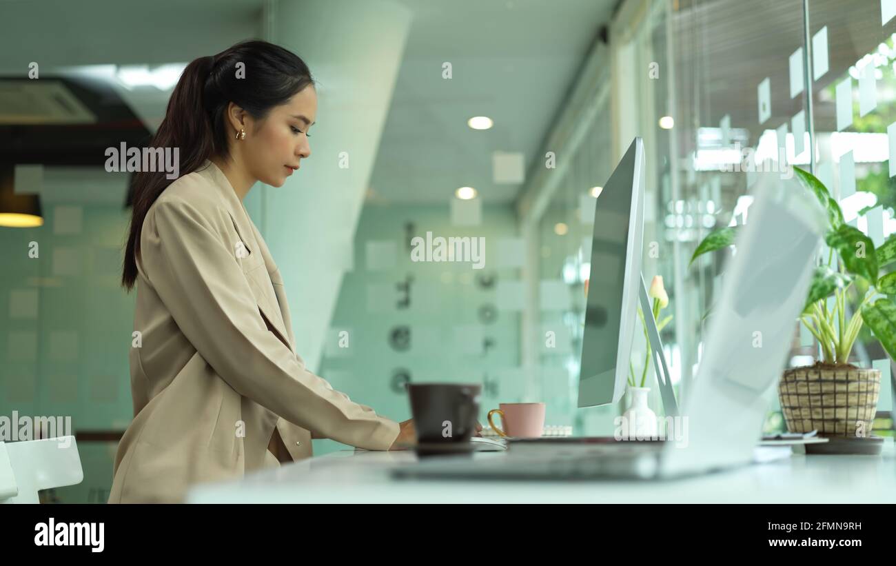 Side view of female office worker typing on computer keyboard on office ...