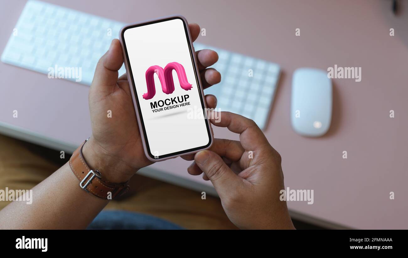 Overhead shot of male office worker holding mock up smartphone while ...