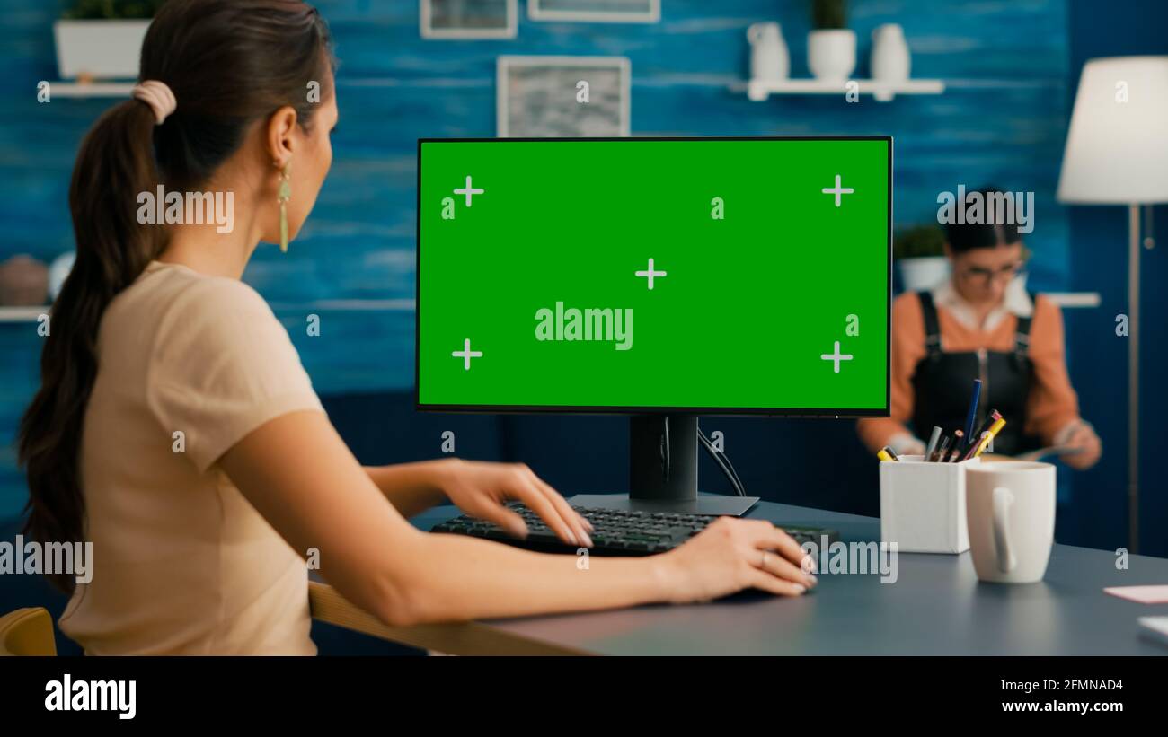 Woman looking at computer with green screen mock up chroma key display ...