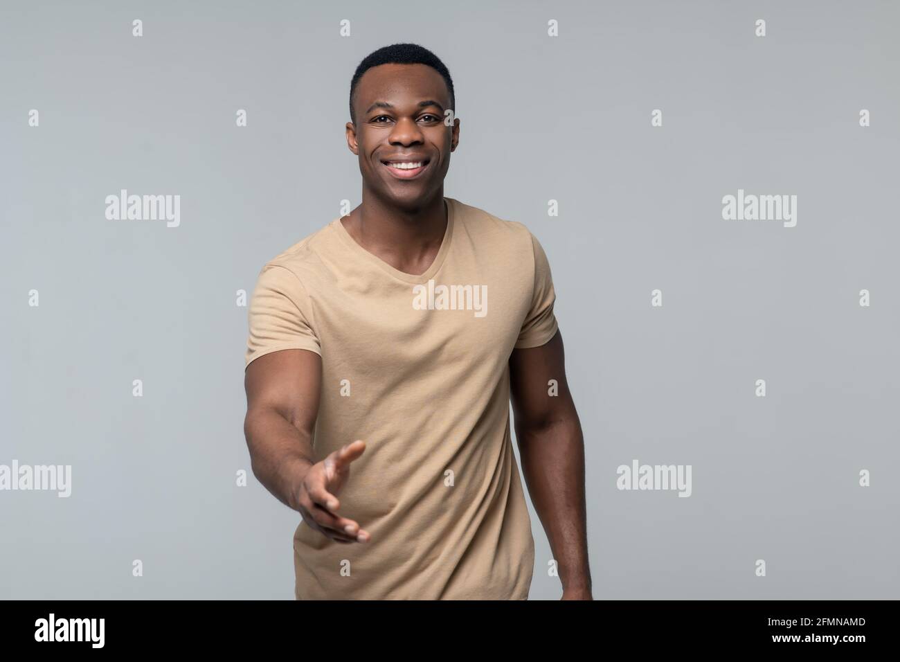 Joyful young man stretching his hand forward Stock Photo - Alamy
