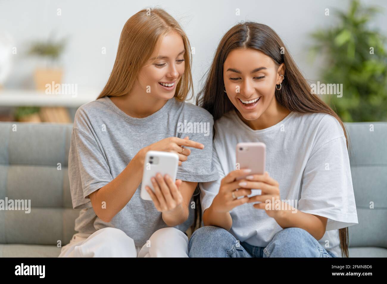 Young women are using phones. Funny girls having fun staying at home ...