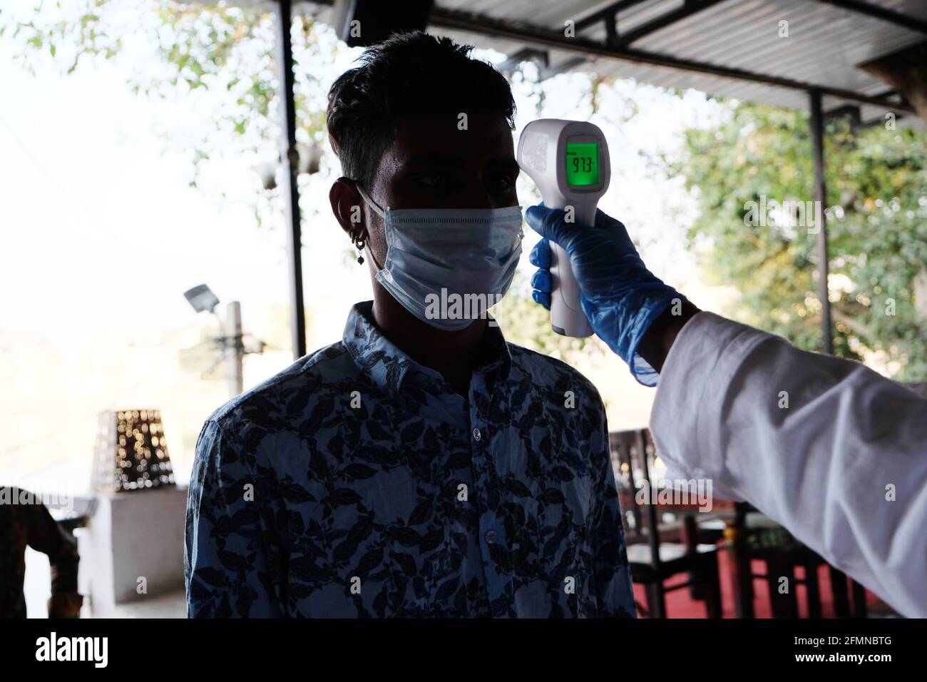 Hand of a medical staff checking temperature for a male guest at a ...