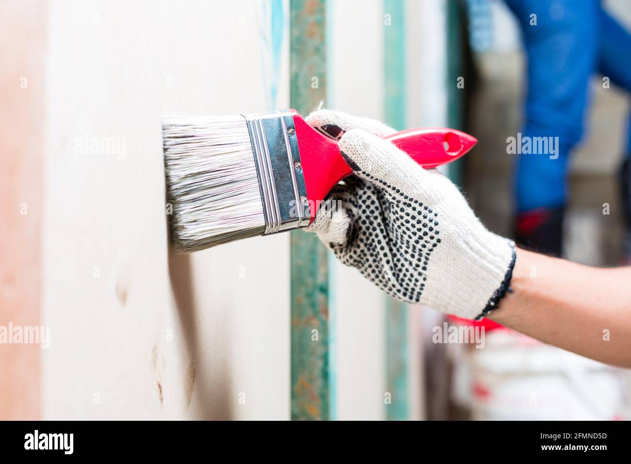 painter painting with a brush, color and protection gloves a wall of a ...