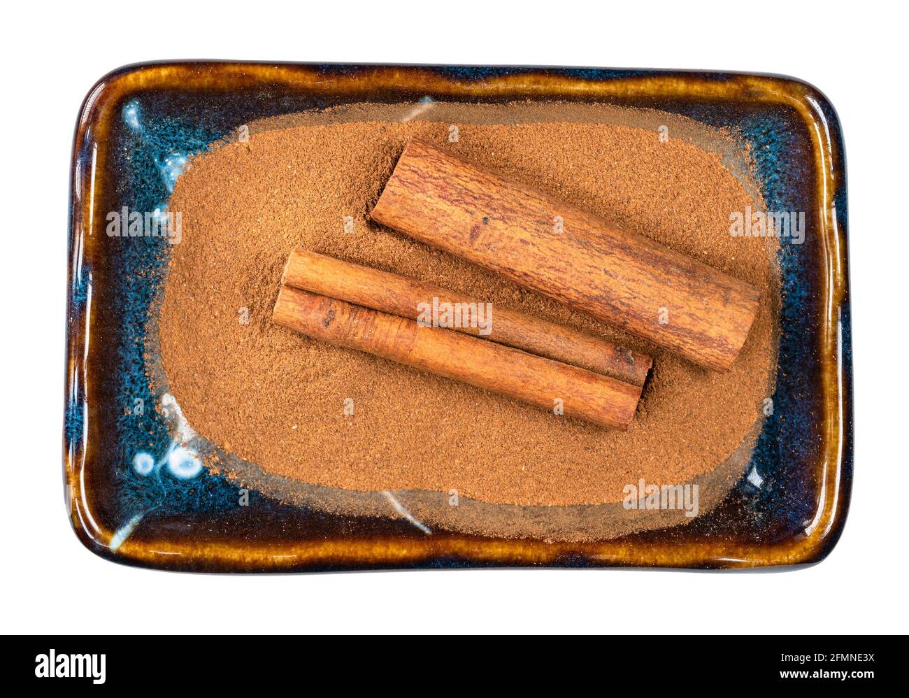 top view of cassia bark and cinnamon powder in ceramic bowl cutout on ...