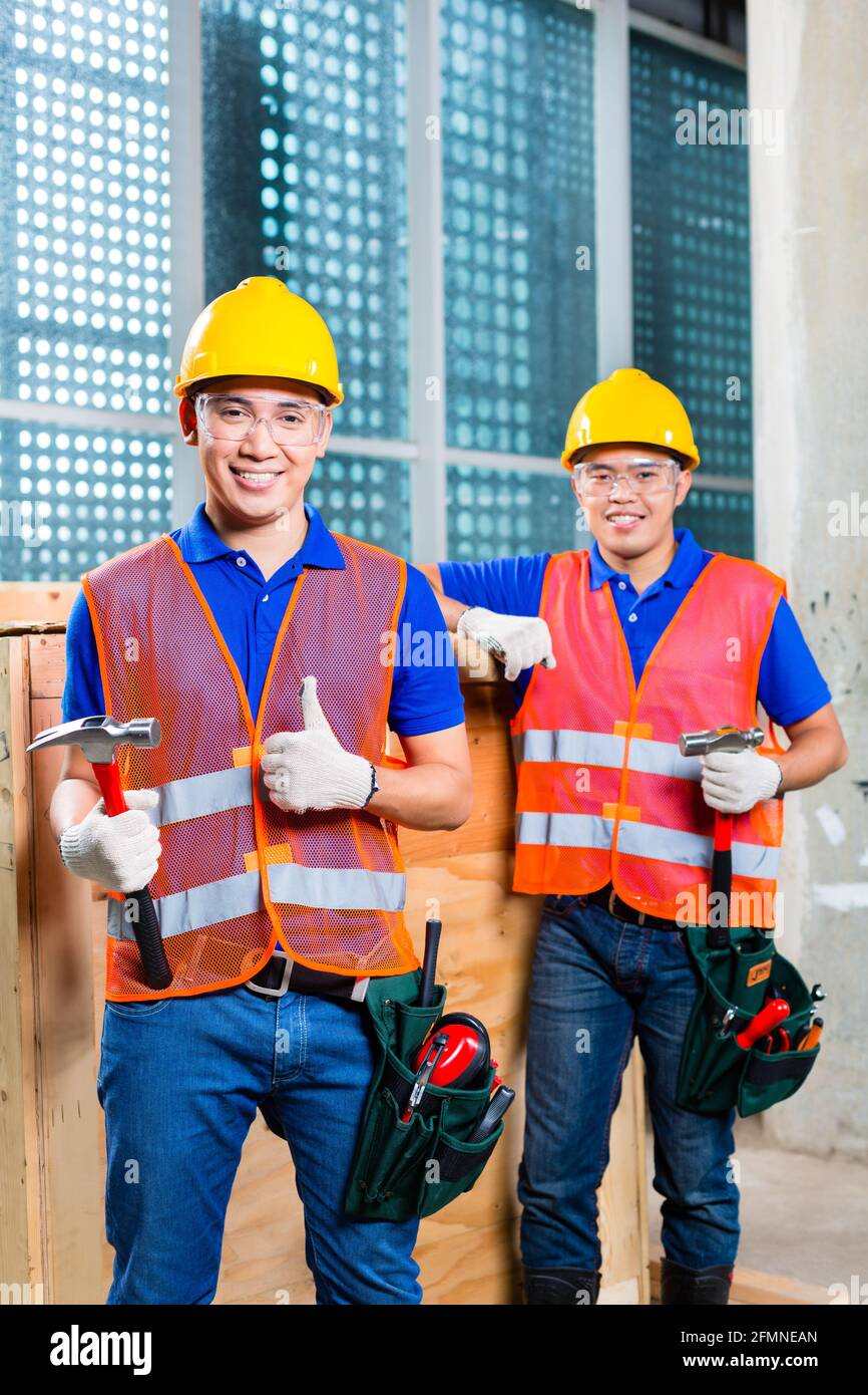 Two Asian Indonesian construction worker on a tower building site close ...