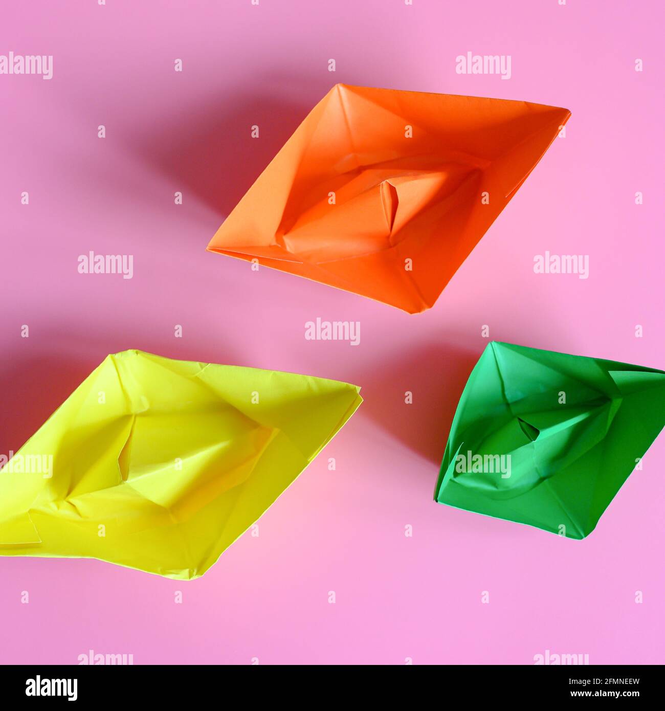 three bright colorful multicolor paper origami boats in orange, yellow ...