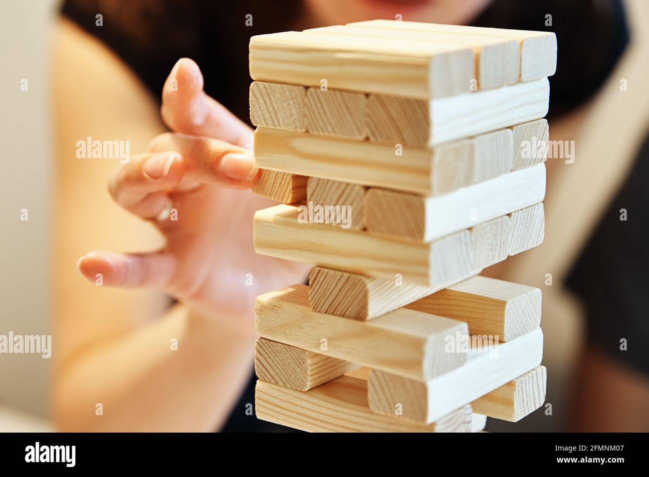 Hand take one block from wooden tower on white background. Family ...
