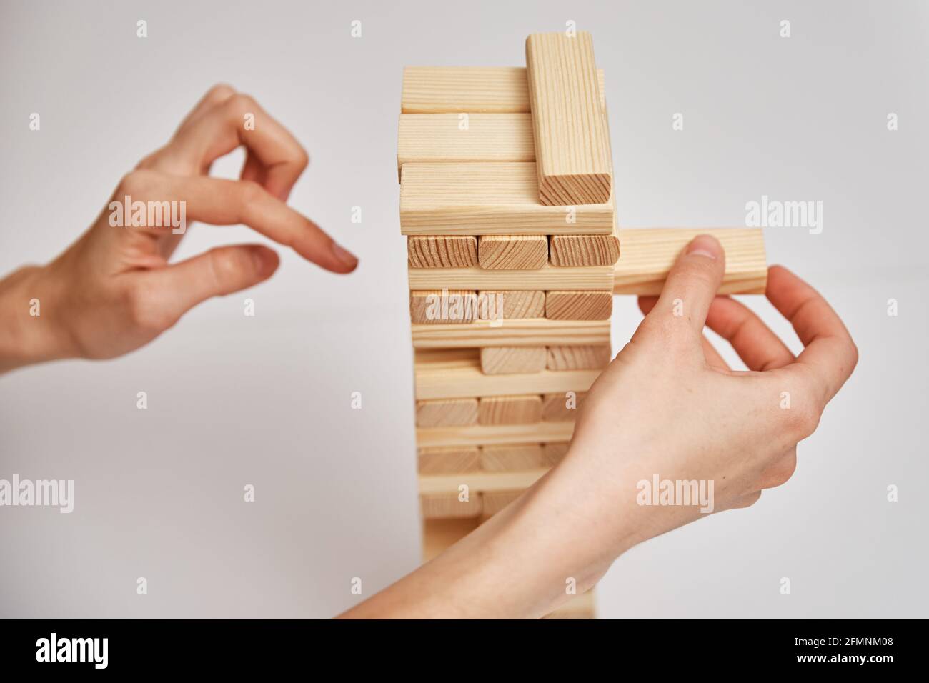 Hand take one block from wooden tower on white background. Family ...