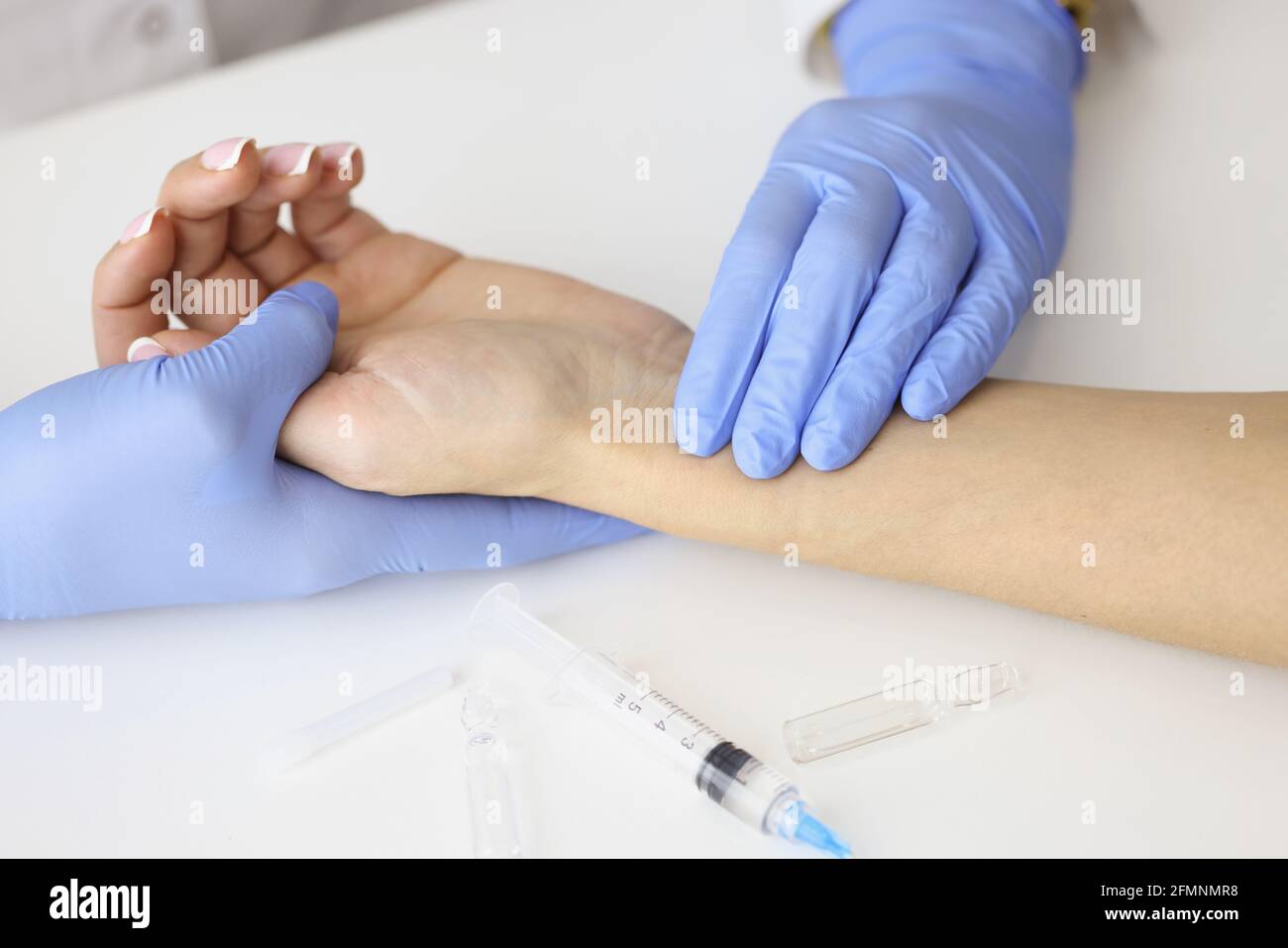 Doctor measuring pulse on patient forearm near empty syringe and ...