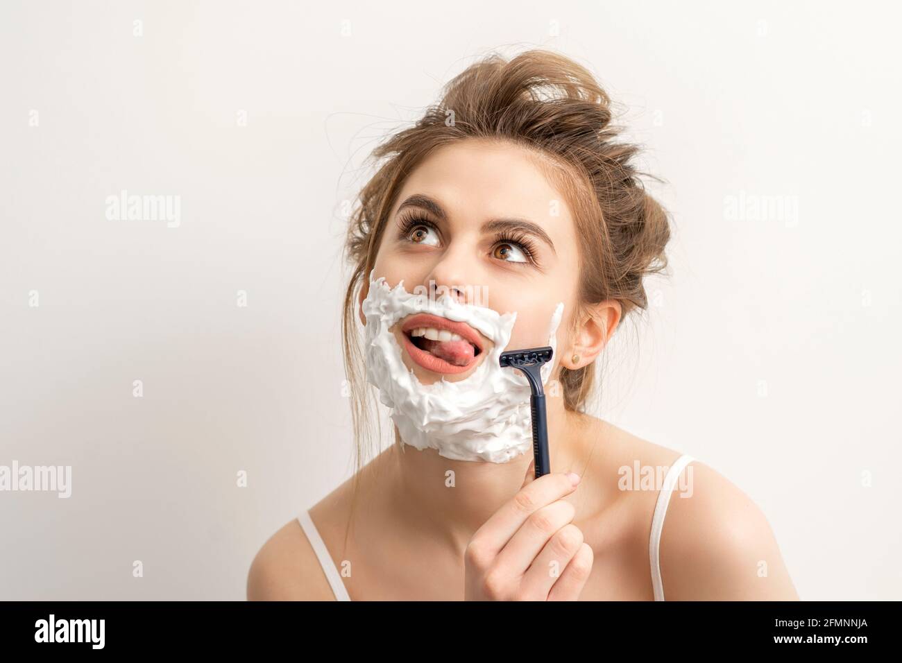 Beautiful young caucasian smiling woman shaving her face with razor ...