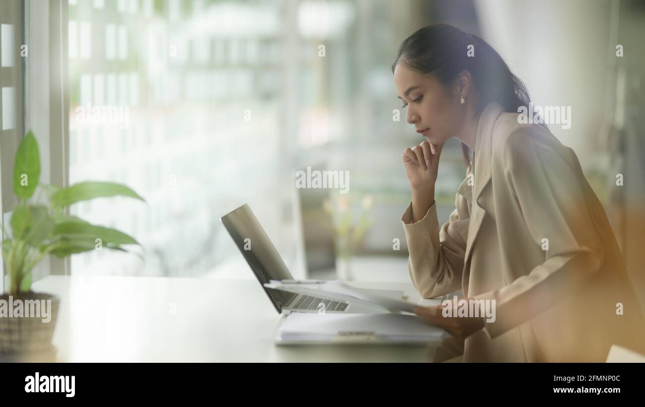 View through glass window of female entrepreneur concentrating on her ...