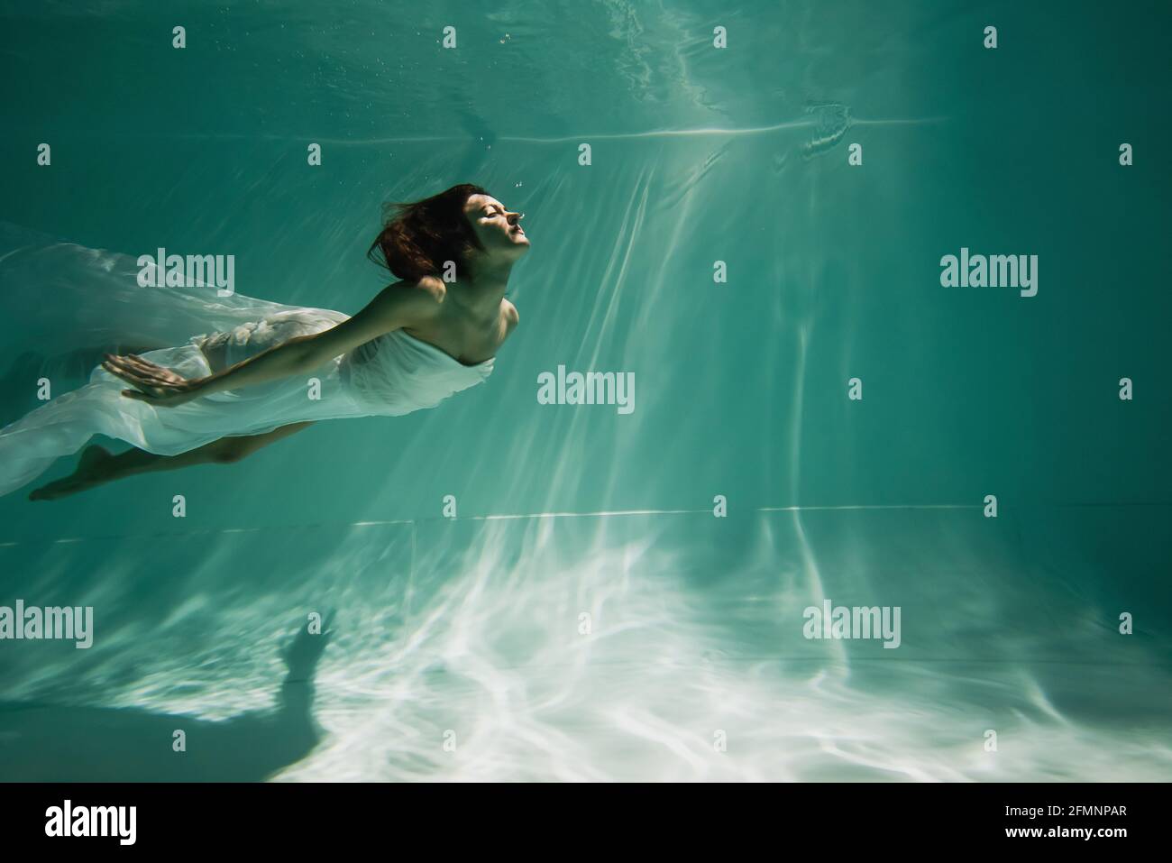 brunette young woman in white elegant dress swimming in pool Stock ...