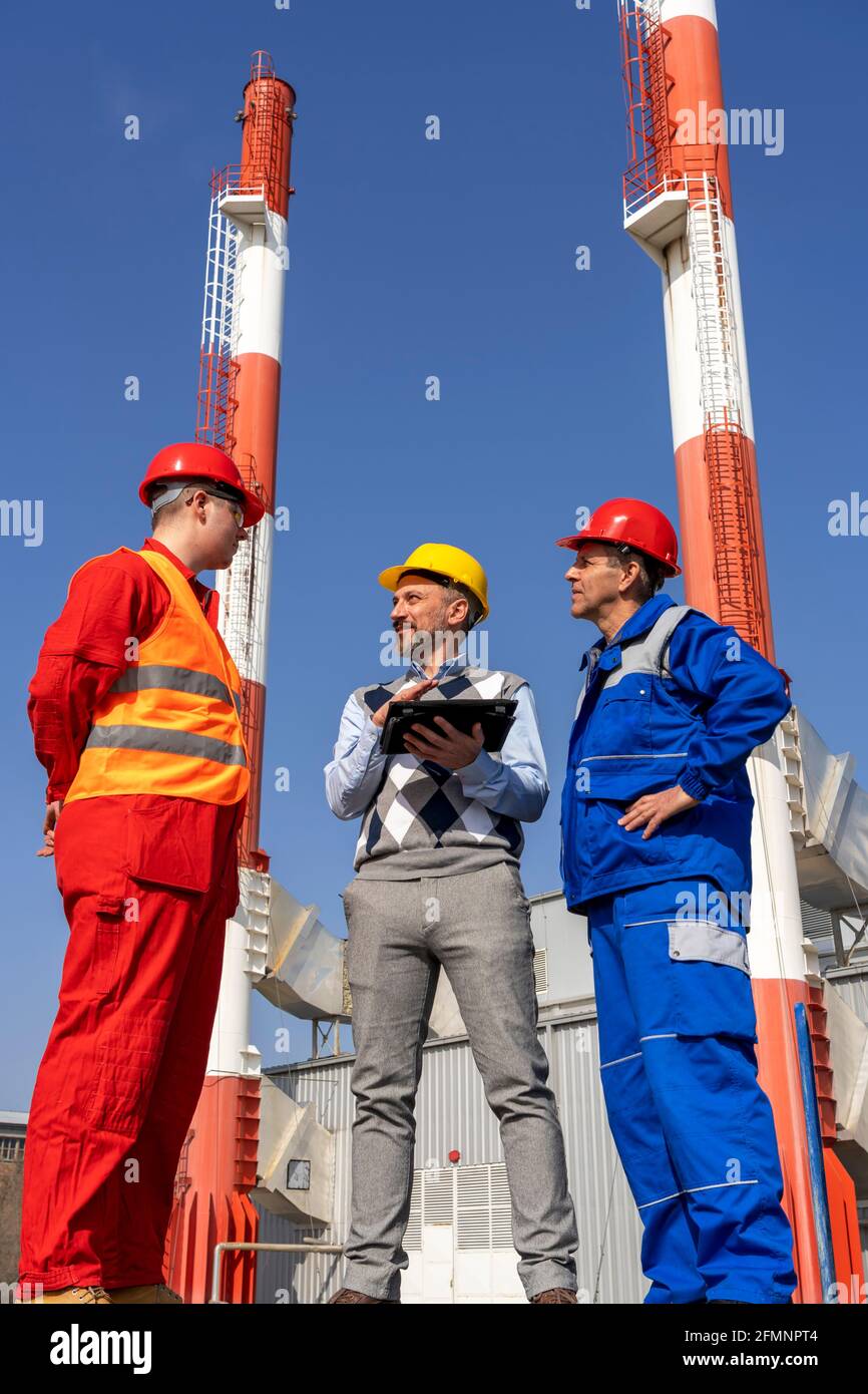 Manager Using Digital Tablet and Discussing with Two Workers Against ...