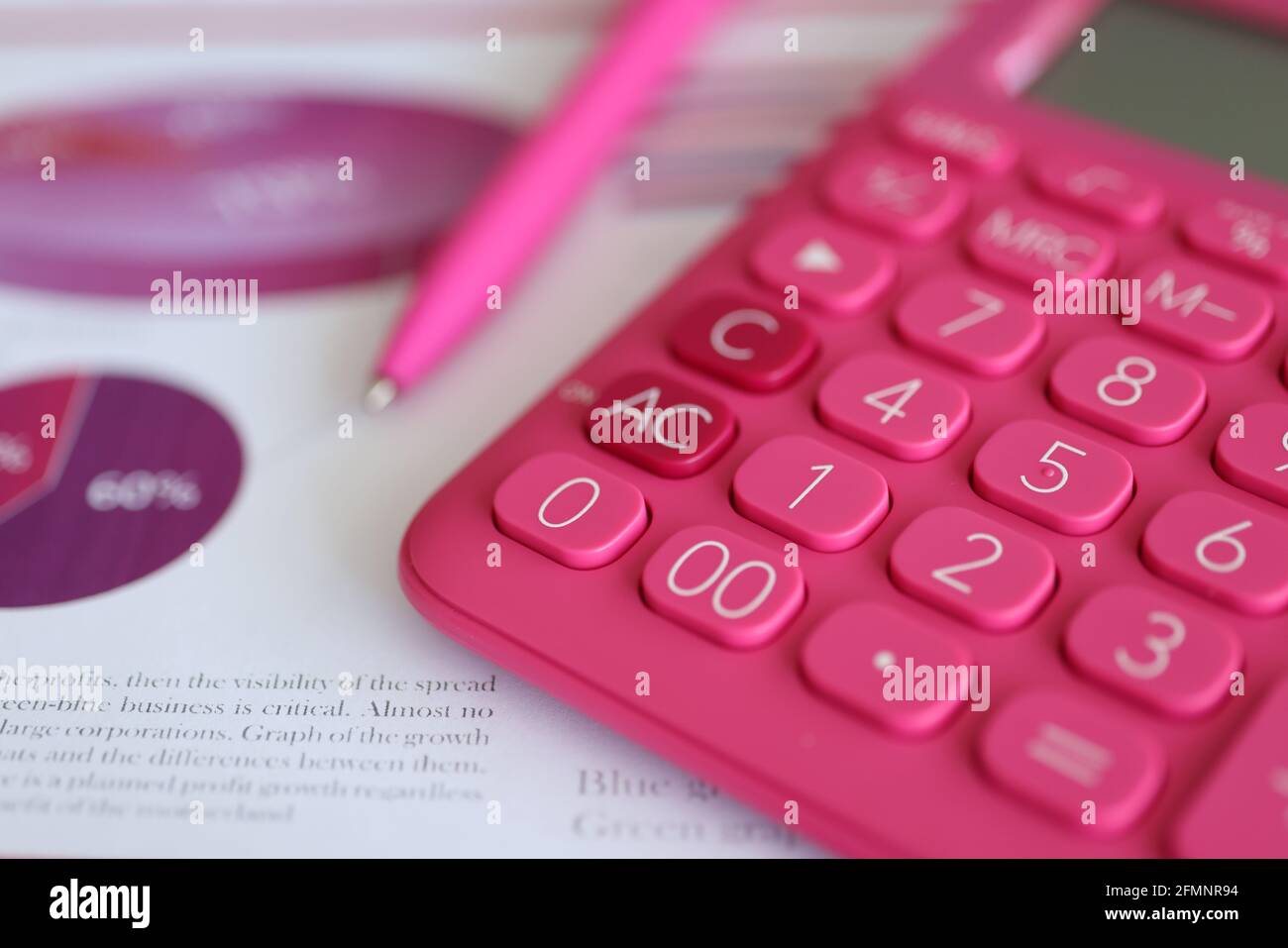 Pink calculator and pen lying on documents with graphs and diagrams ...