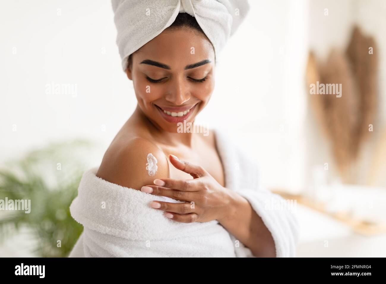 Black Lady Applying Cream On Shoulders Moisturizing Skin In Bathroom ...