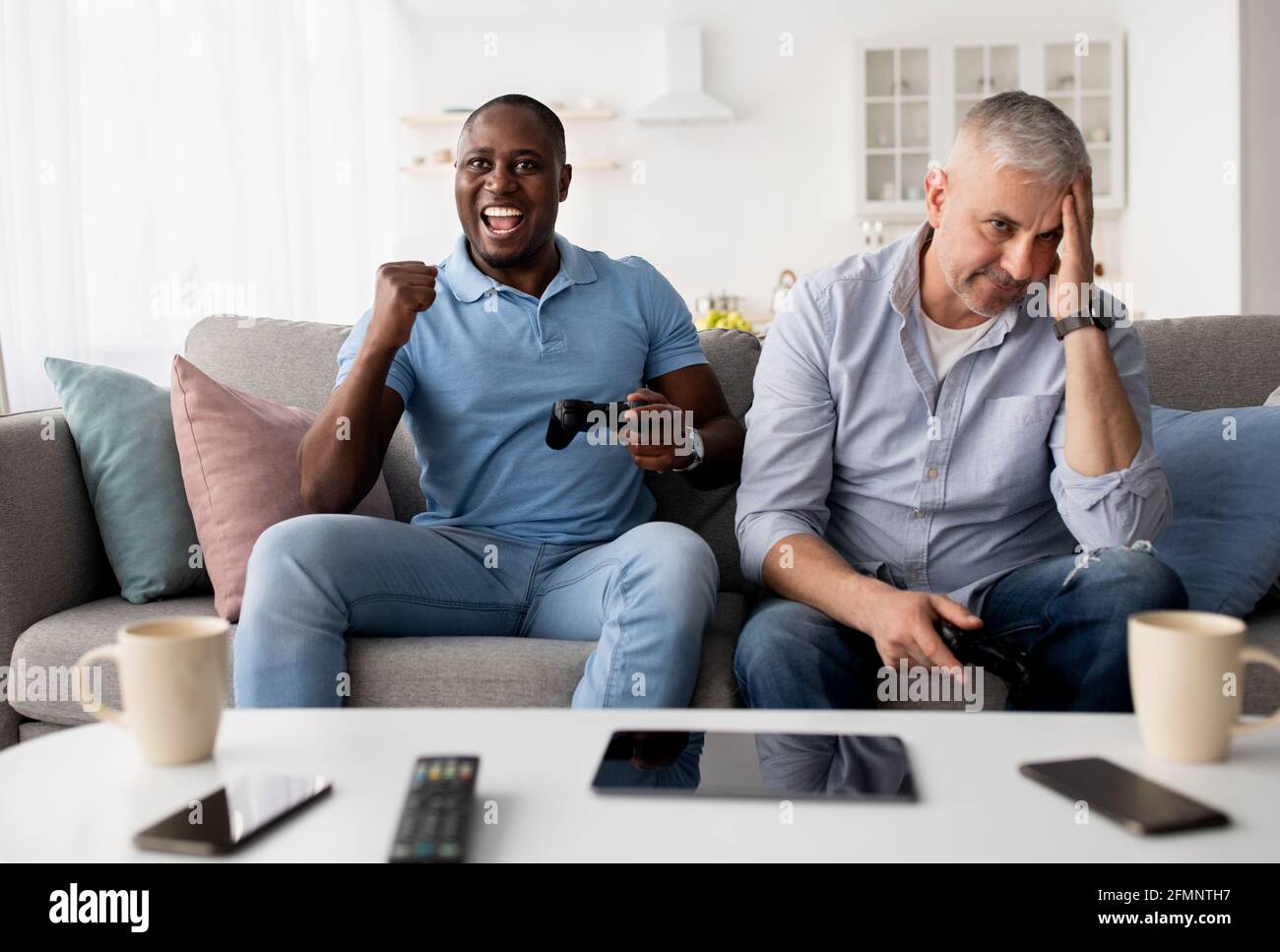 Friends enjoying playing video game on playstation, resting at home ...