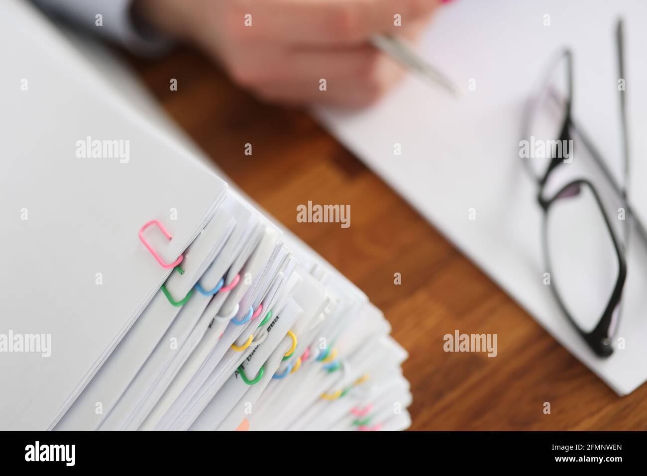 Lot of documents with colored paper clips lying on desktop closeup ...