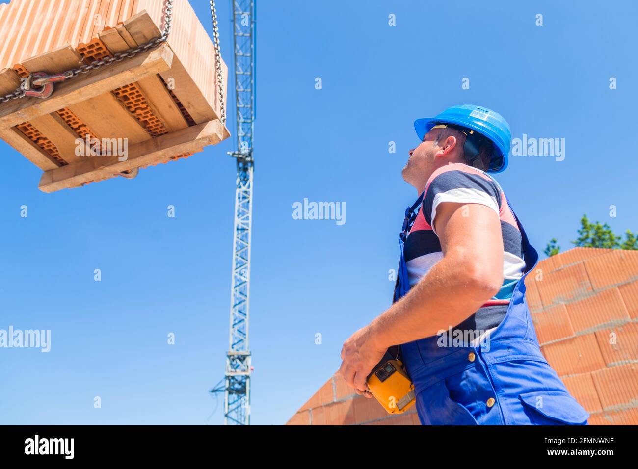 Crane driver deliver a pallet bricks on construction or building site ...