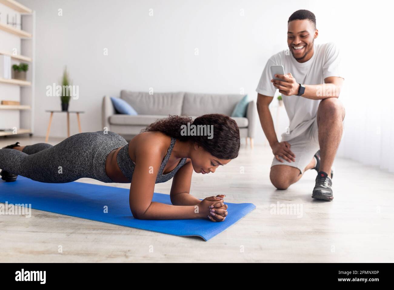 Young black couple working out as team at home, fit lady standing in ...