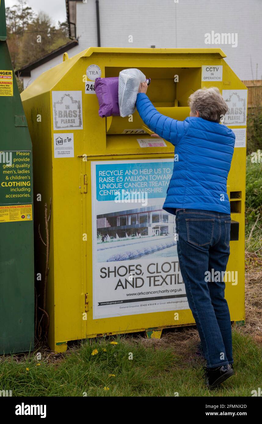 Hampshire, England, UK. 2021. Woman donating clothing for charity using ...
