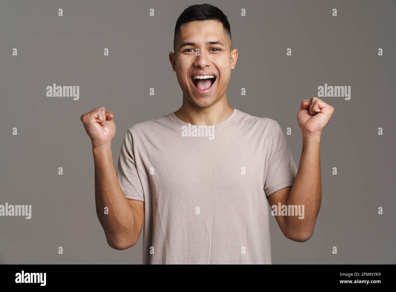 Excited handsome guy exclaiming and making winner gesture isolated over ...