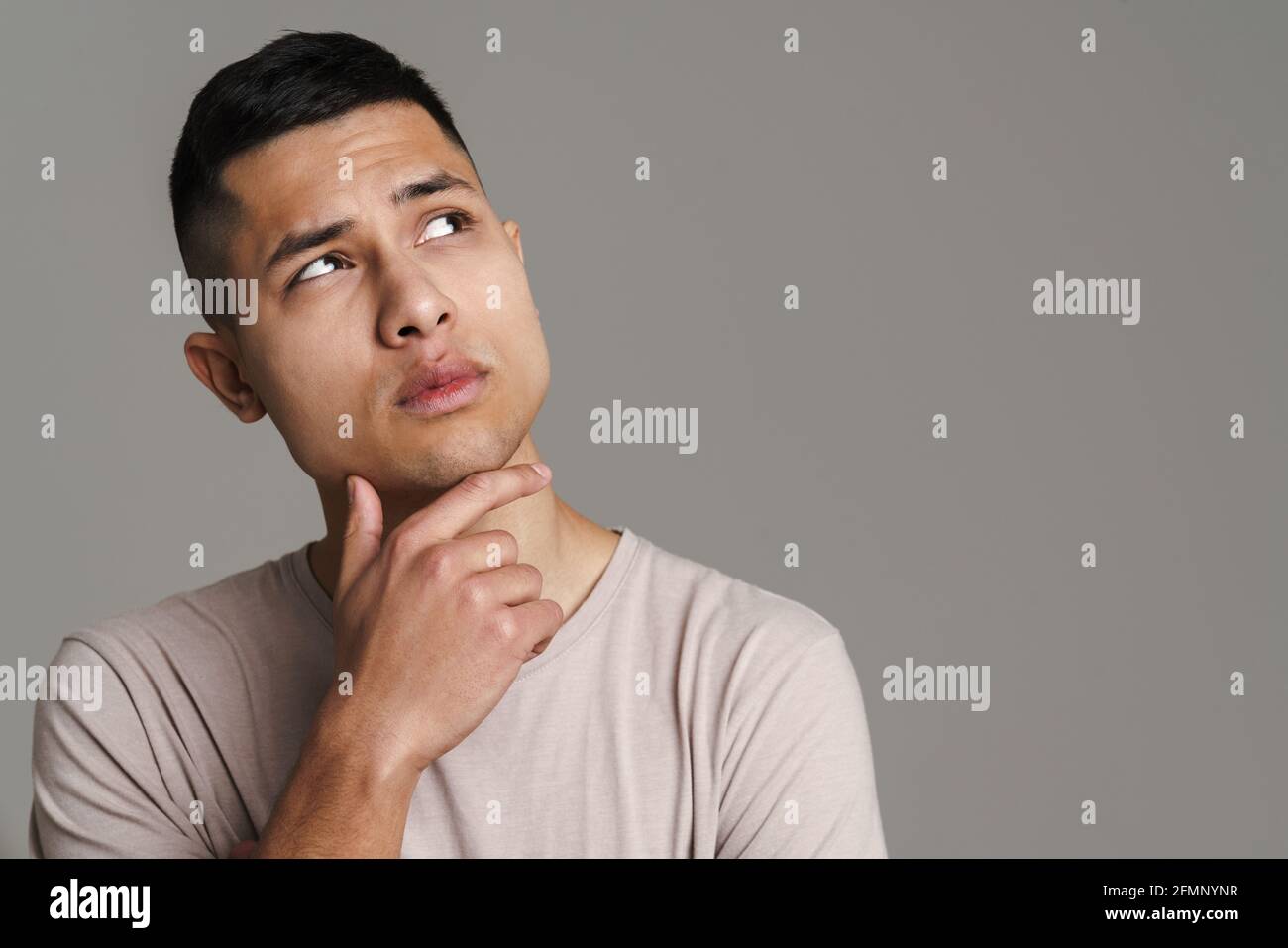 Brunette young puzzled man thinking and looking upward isolated over ...