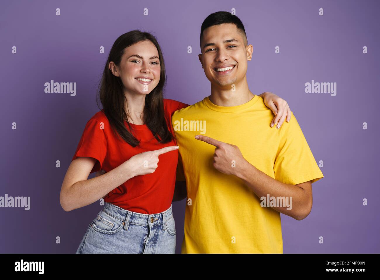 Happy couple hugging and pointing fingers at each other isolated over ...