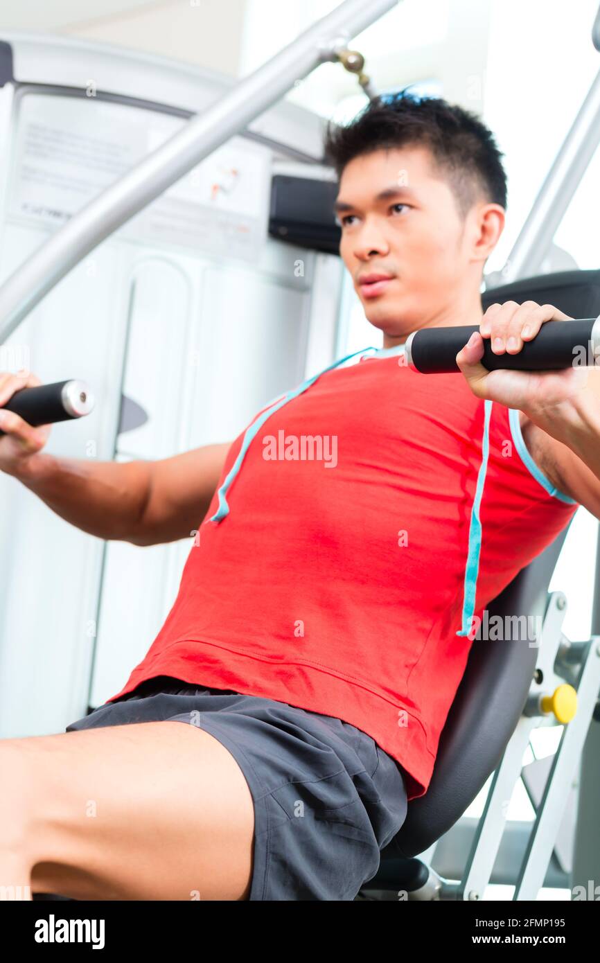Asian Chinese man having fitness training or workout in gym doing sport ...