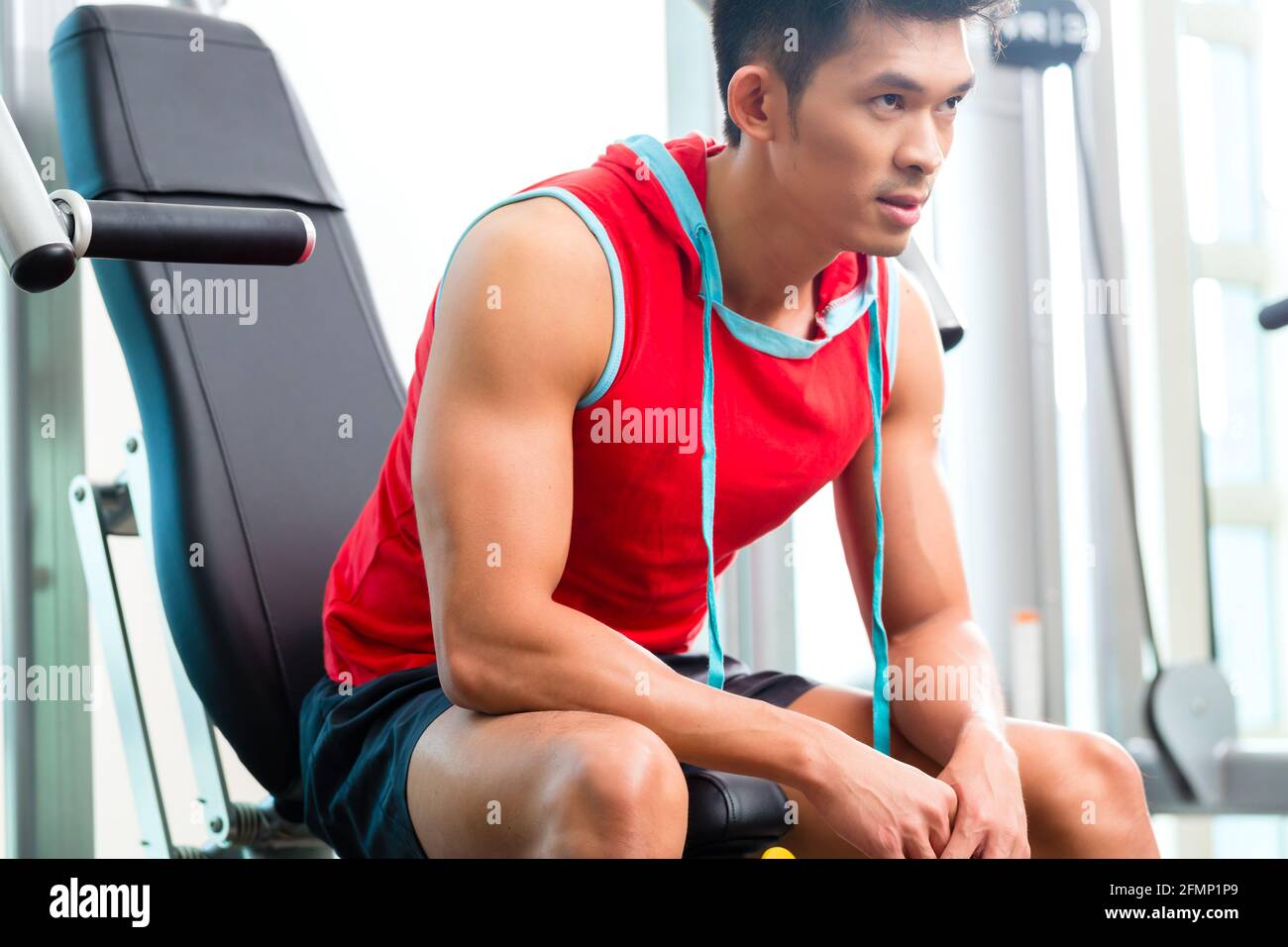 Asian Chinese man having fitness training or workout in gym doing sport ...