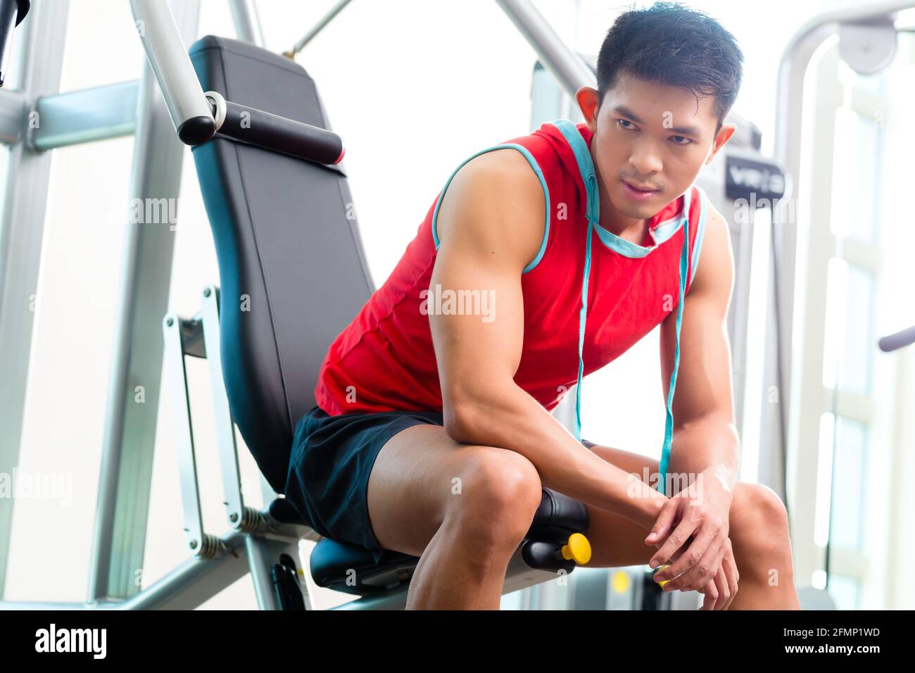 Asian Chinese man having fitness training or workout in gym doing sport ...